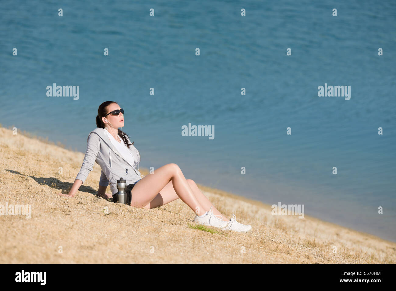Summer active woman sit on beach sunset in fitness outfit Stock Photo ...