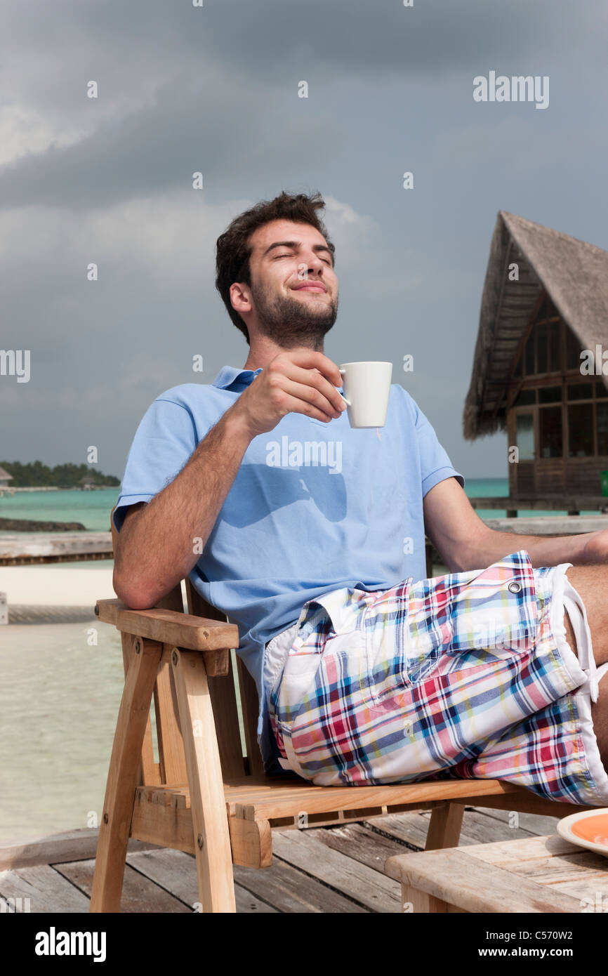 Man drinking coffee on deck at beach Stock Photo - Alamy