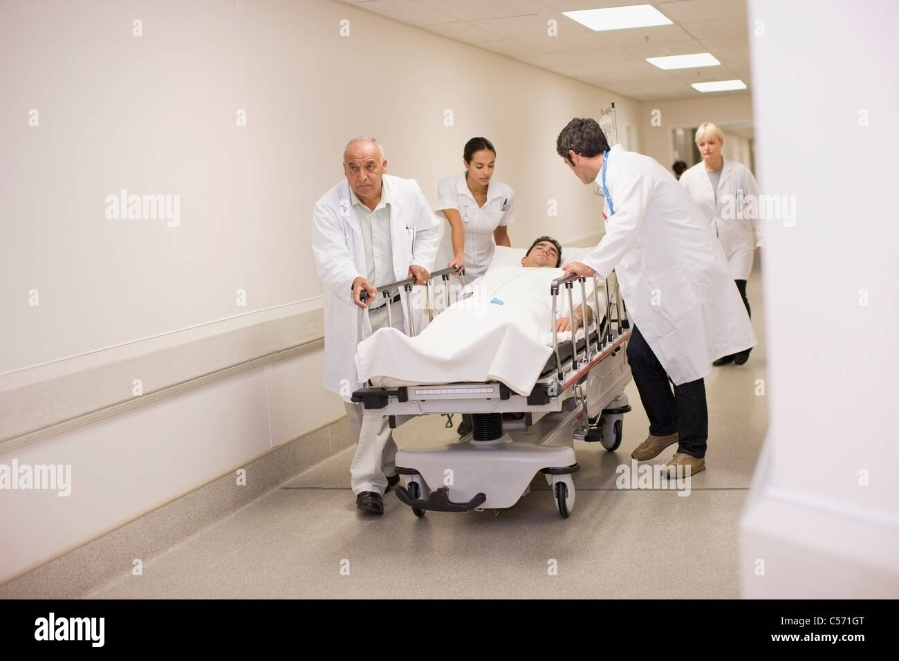 Doctors rushing patient down hallway Stock Photo - Alamy