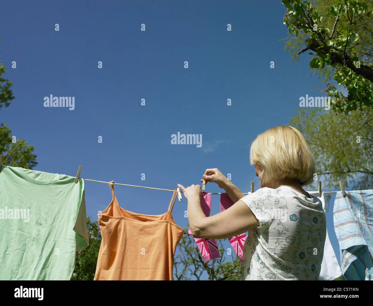 Woman hanging clothes on clothesline Stock Photo - Alamy