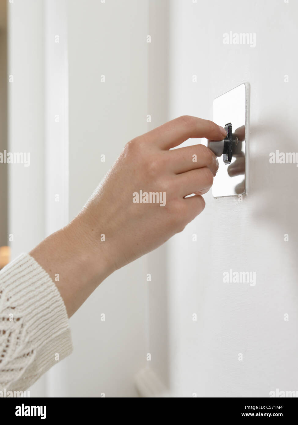 Woman turning on light switch Stock Photo - Alamy