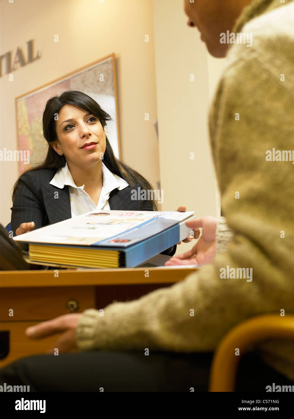 Businesswoman passing folder to client Stock Photo - Alamy