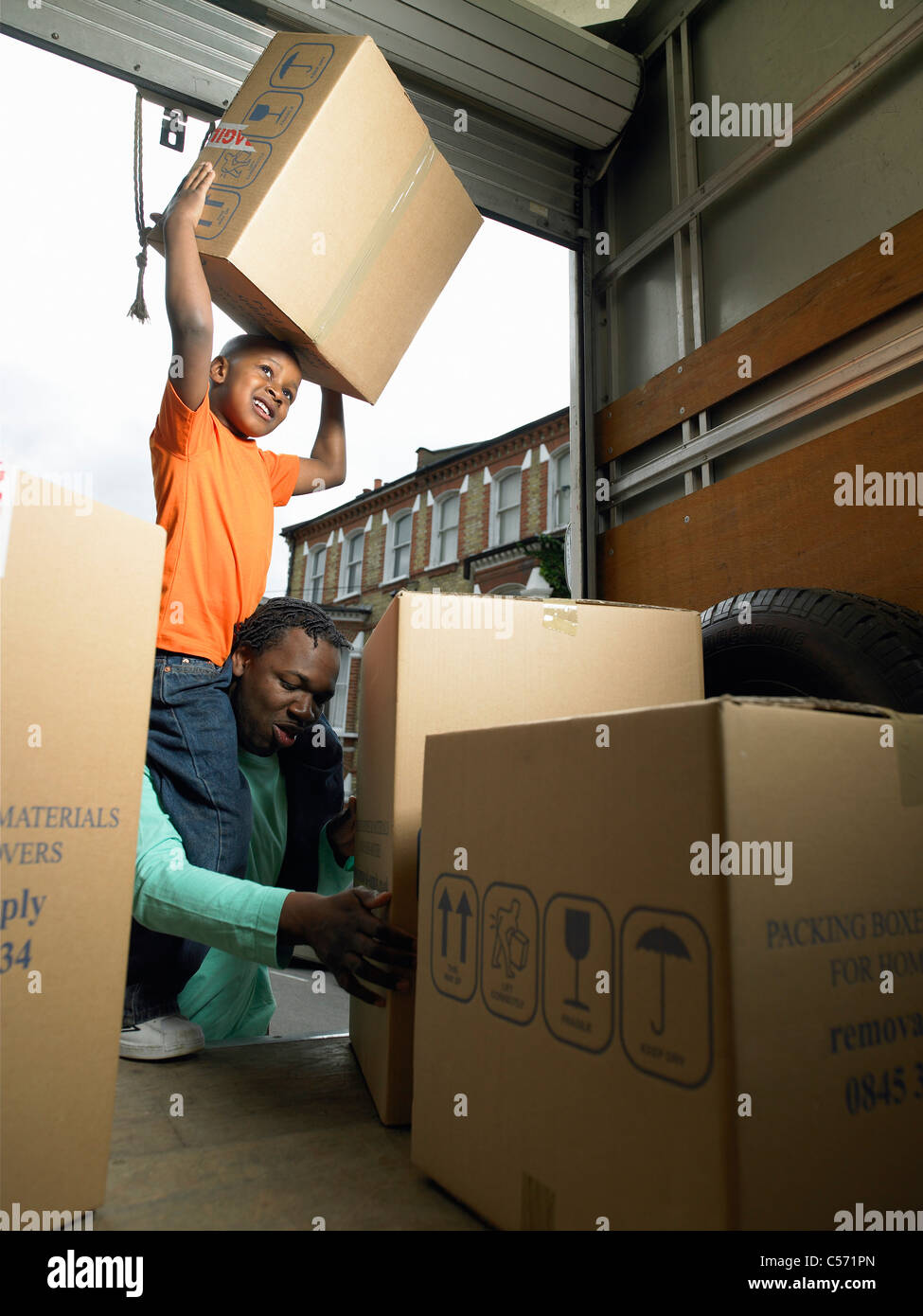 Family unpacking boxes from moving van Stock Photo - Alamy