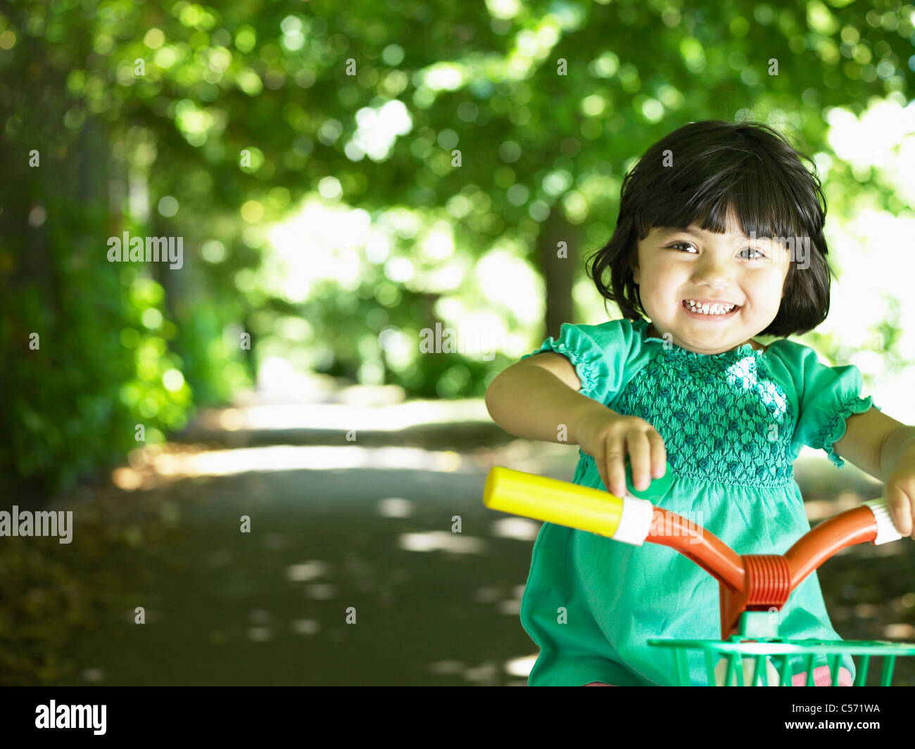 Smiling toddler girl riding bike Stock Photo - Alamy