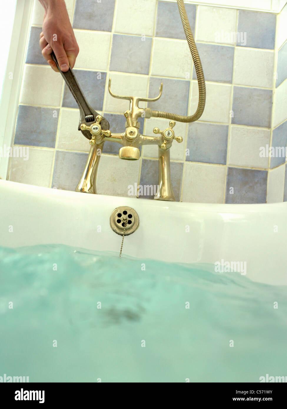 Man using wrench to fix bathtub Stock Photo - Alamy