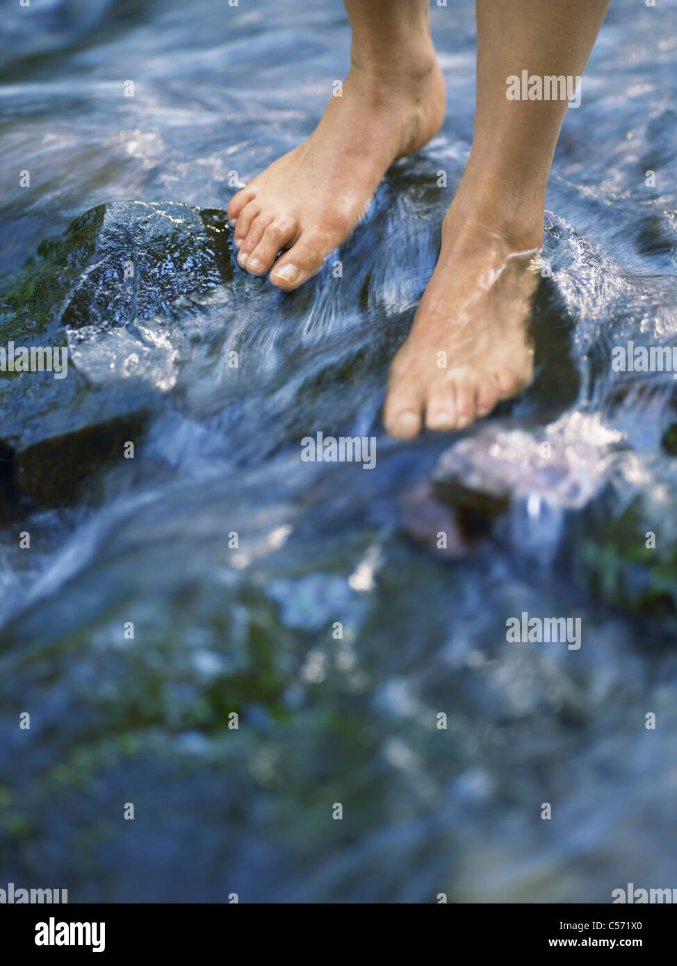Feet walking on river rocks Stock Photo - Alamy