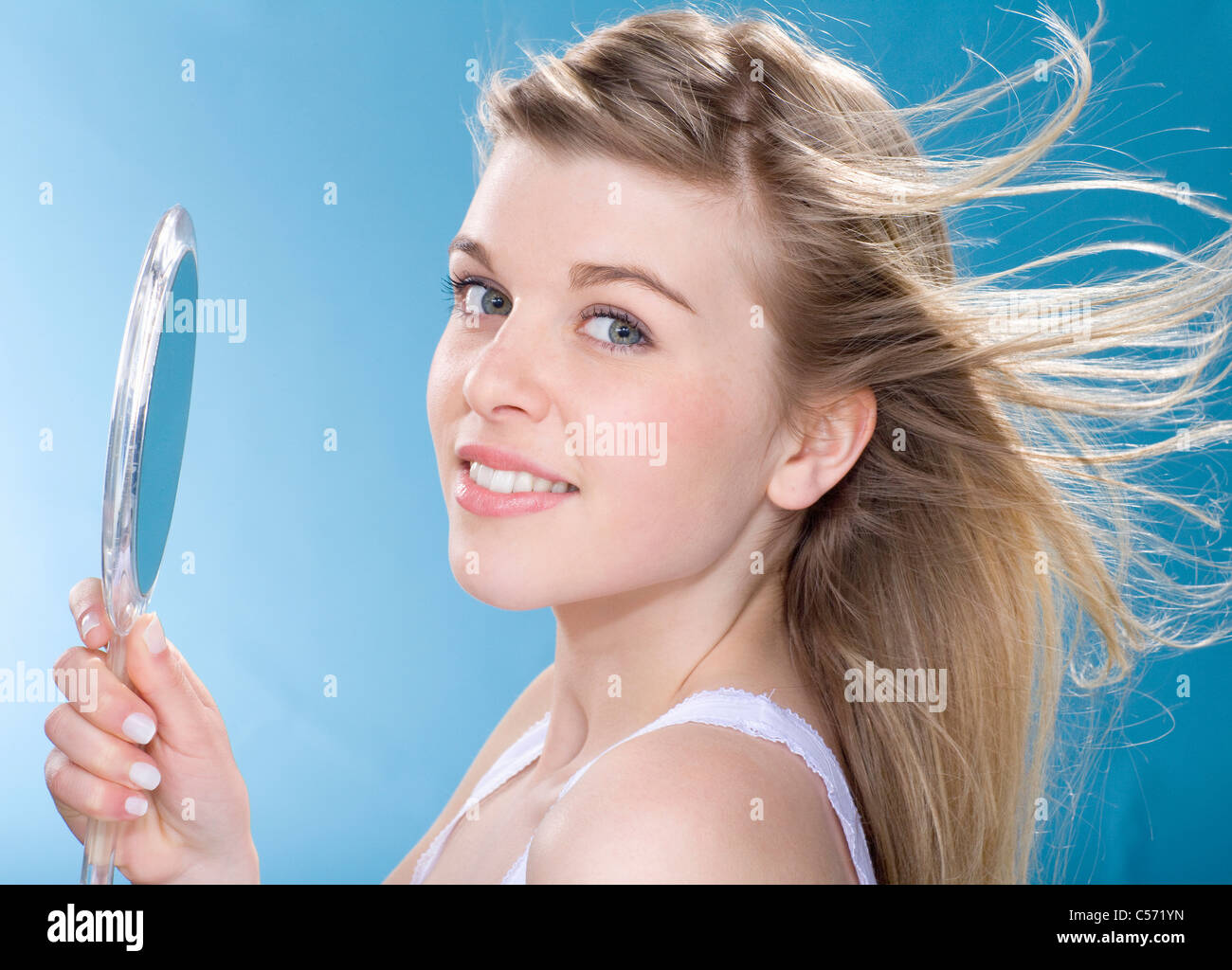 Smiling girl using hand mirror Stock Photo - Alamy