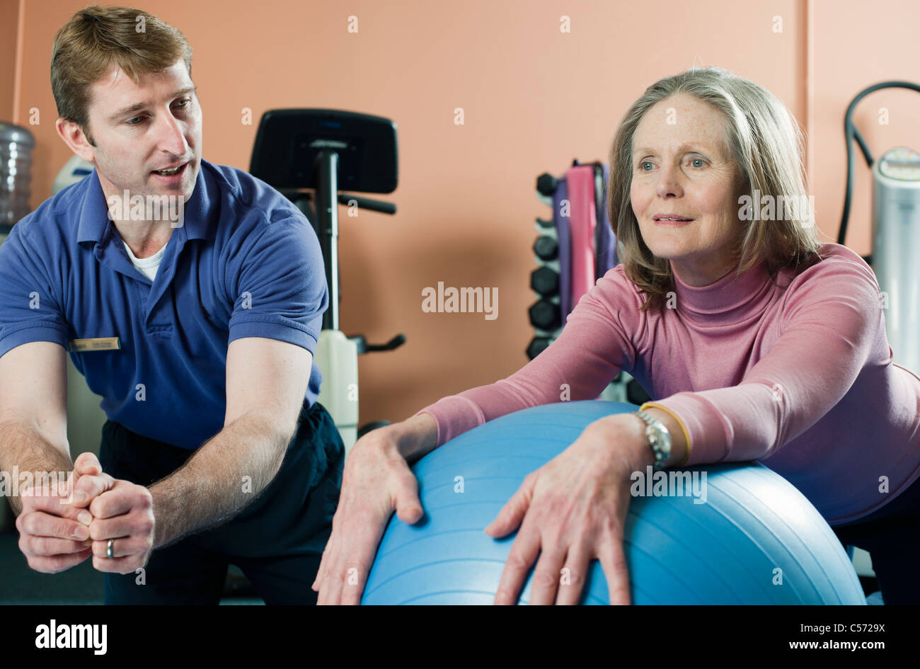 Trainer helping older woman exercise Stock Photo - Alamy