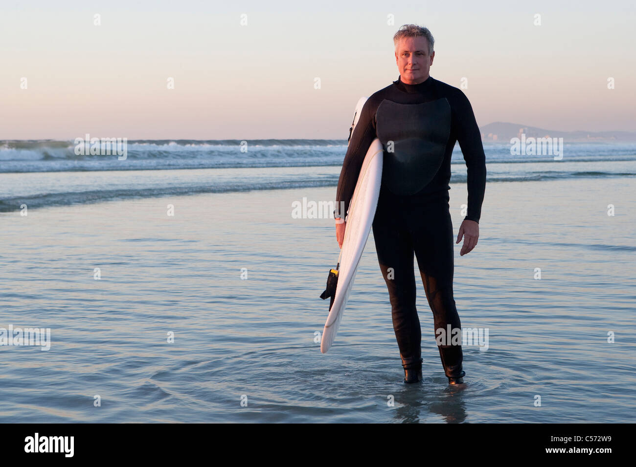 Surfer standing in water Stock Photo - Alamy