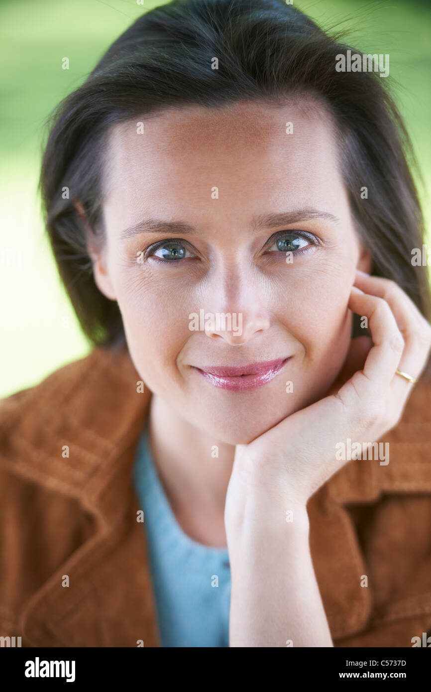 Smiling woman resting chin in hand Stock Photo - Alamy