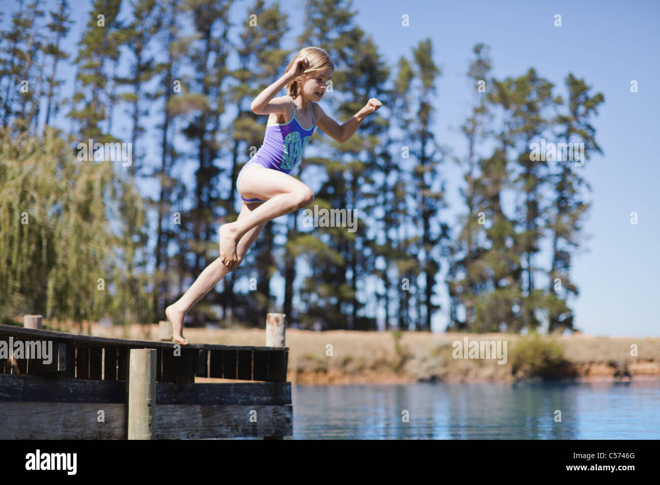 Girl jumping into lake from jetty Stock Photo - Alamy