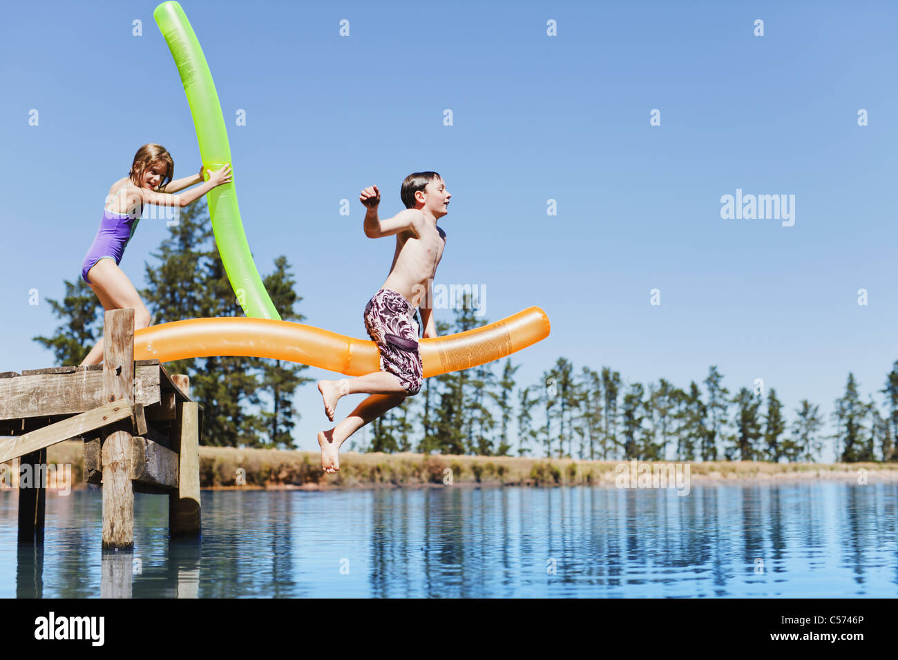 Children jumping into lake from jetty Stock Photo - Alamy
