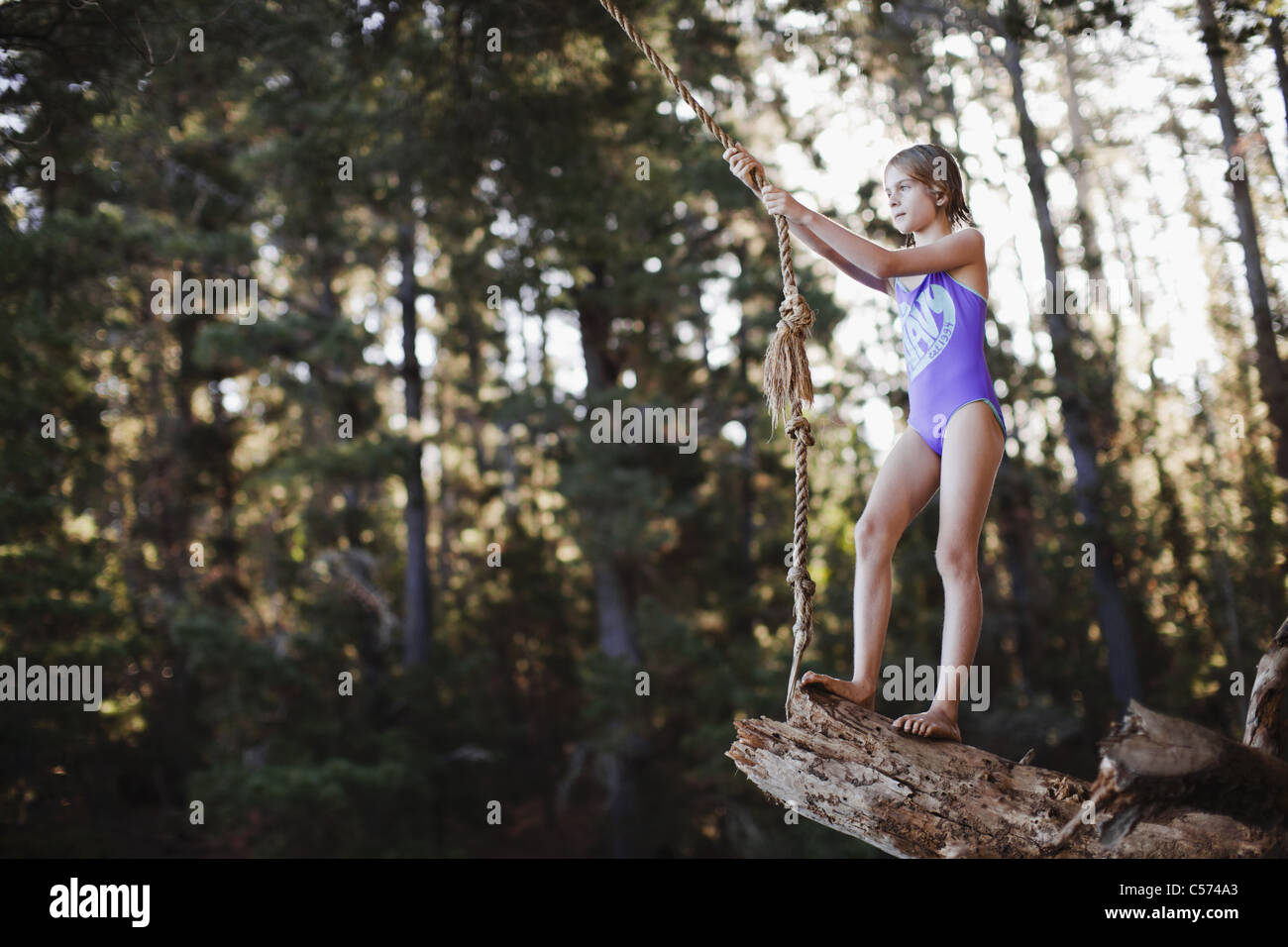 Young girl using rope swing over lake Stock Photo - Alamy