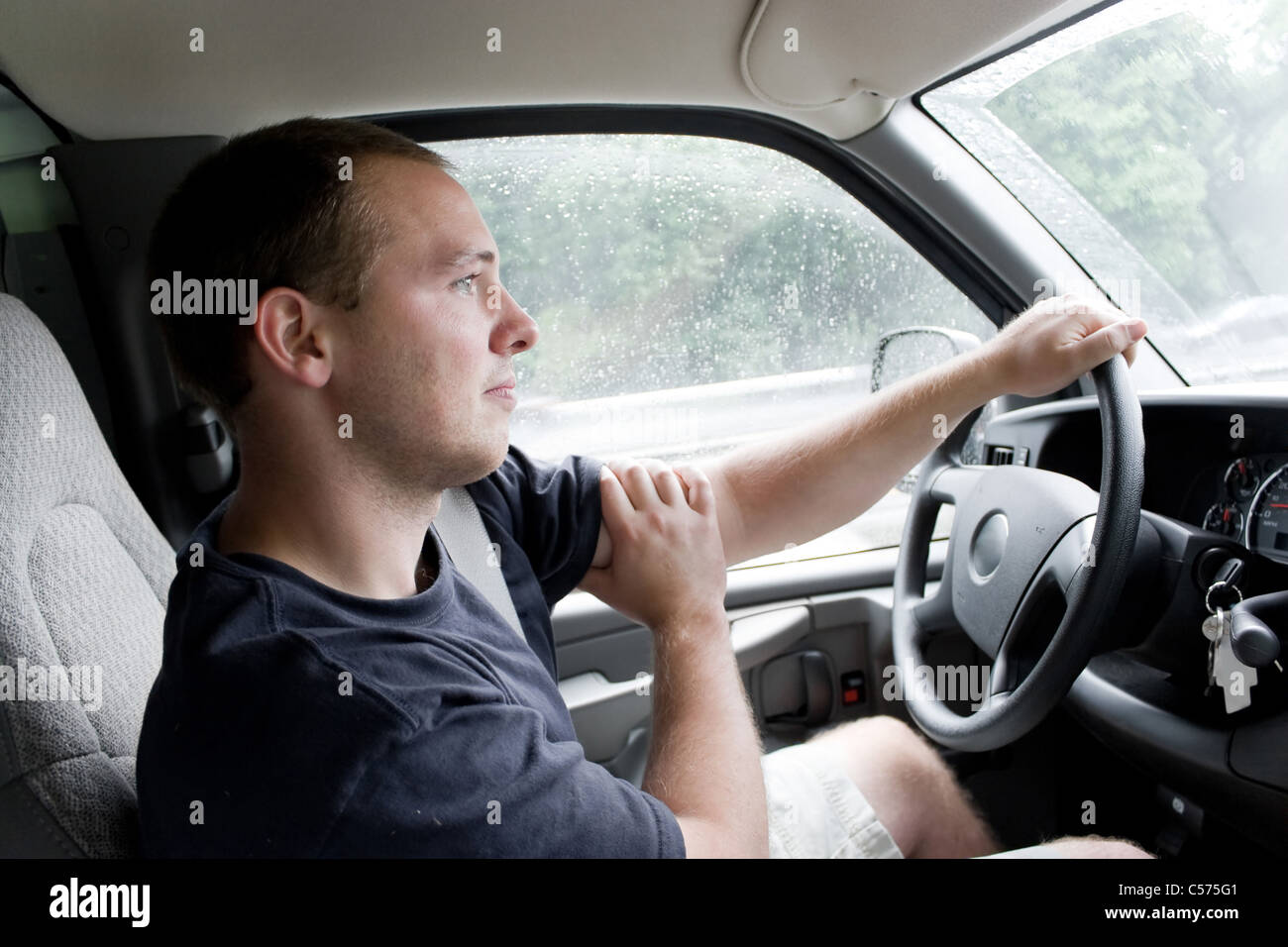 Interior view of a young man driving a van or truck. Shallow depth of ...