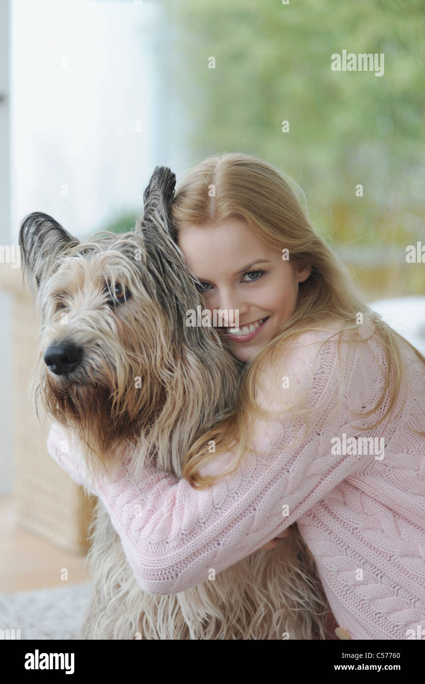 Smiling woman hugging dog at home Stock Photo - Alamy