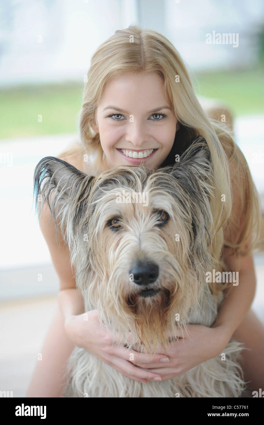 Smiling woman hugging dog at home Stock Photo - Alamy