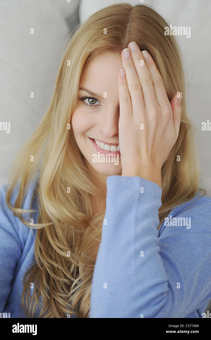 Smiling woman covering one eye Stock Photo - Alamy