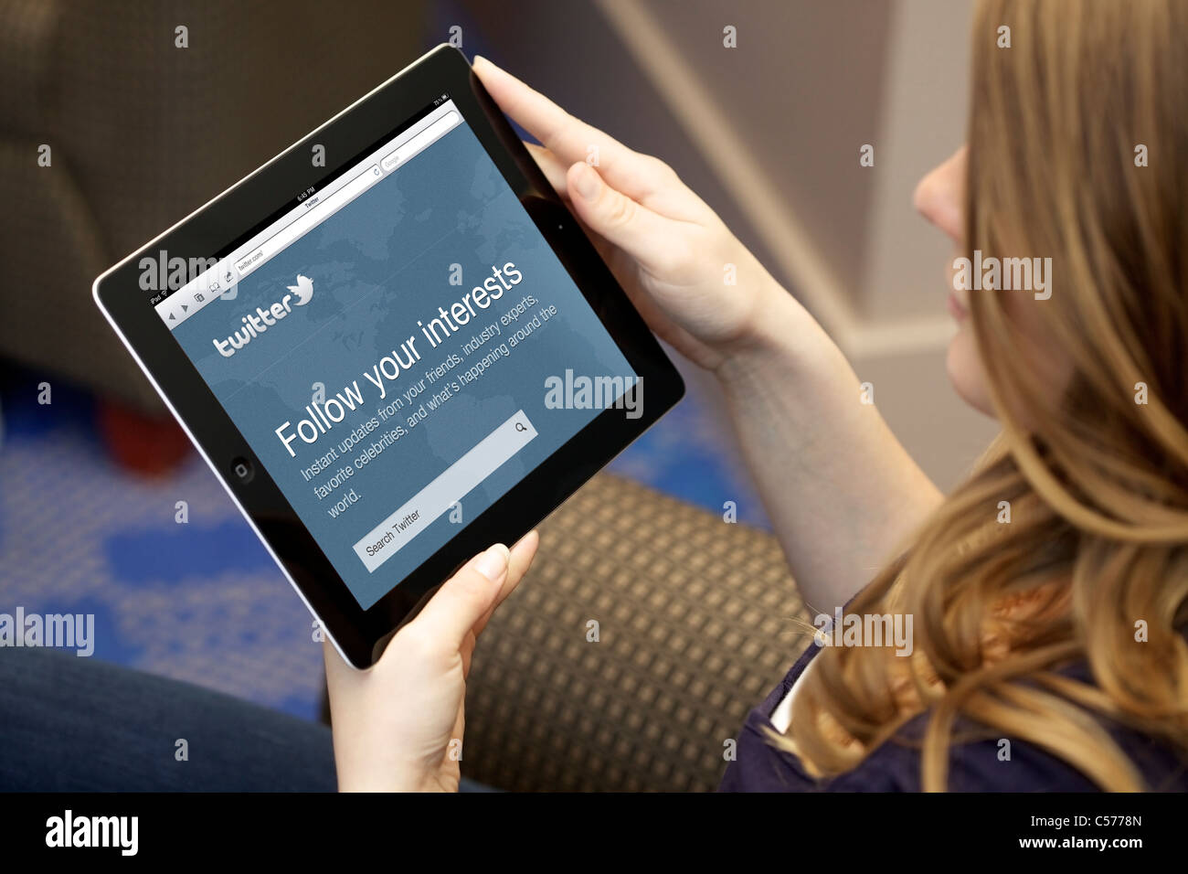 Close up picture of a happy young woman checking Twitter social networking website on an iPad 2 ...