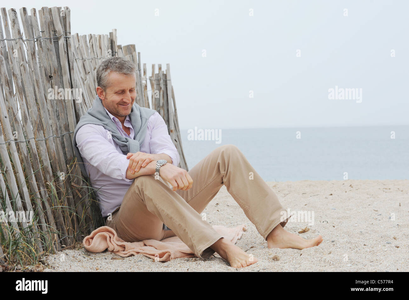 Man sitting in sand on beach Stock Photo - Alamy
