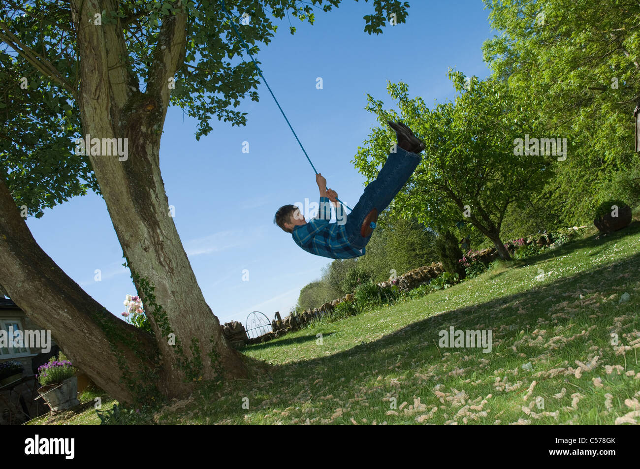Boy swinging on garden rope hi-res stock photography and images - Alamy