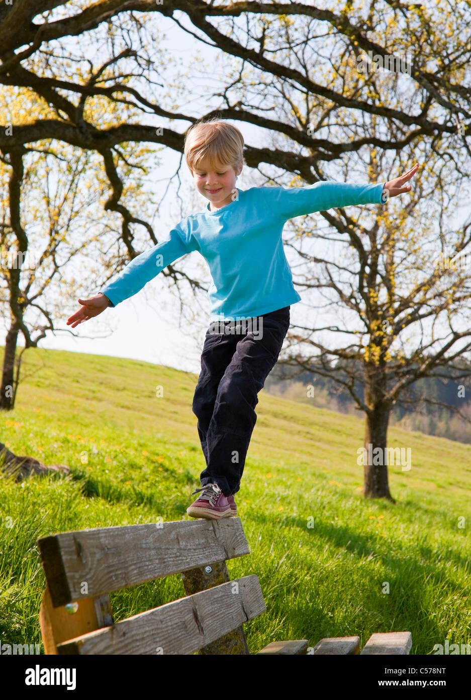Boy balancing along park bench Stock Photo - Alamy