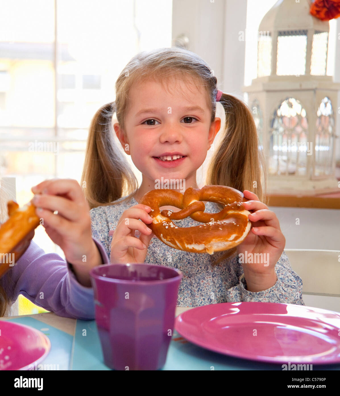 Girls eating pretzels at table Stock Photo - Alamy