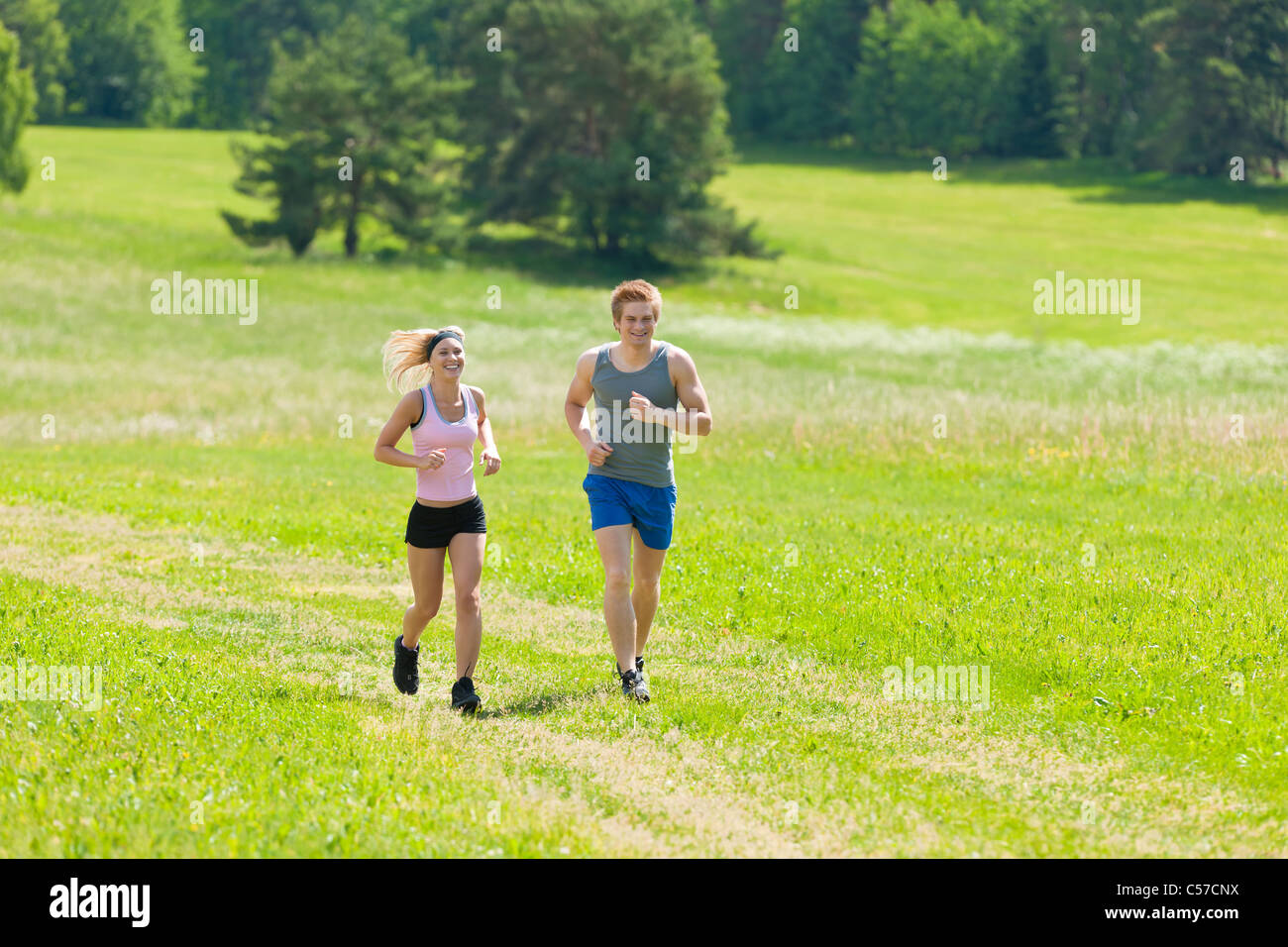 Young fit couple jogging on summer day in meadows countryside Stock ...