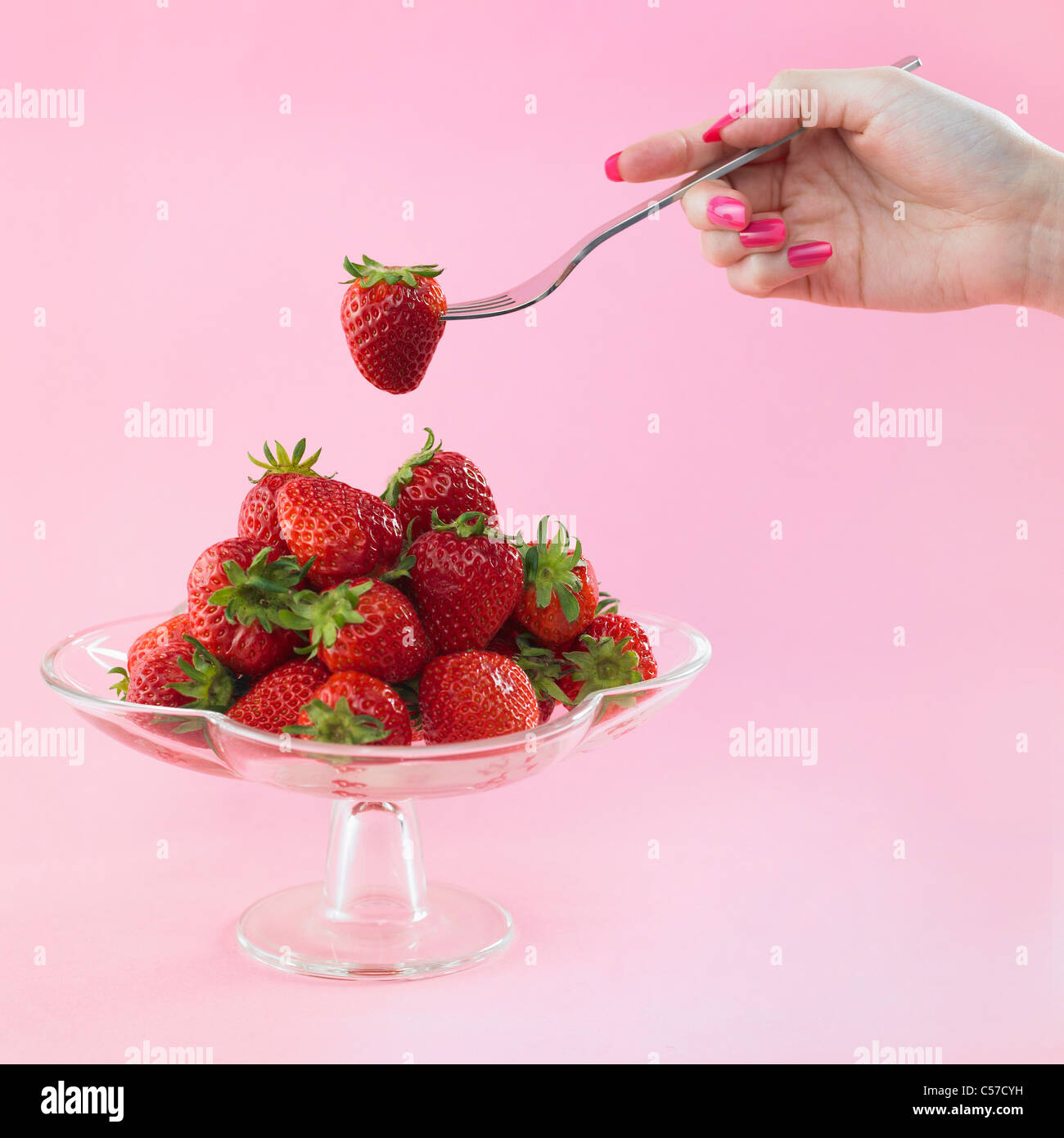 pink colored nail hand poking strawberry Stock Photo - Alamy