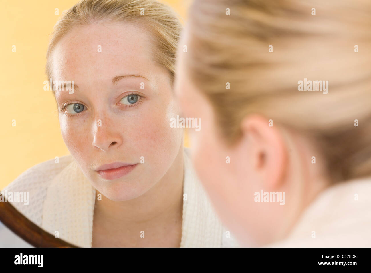 Woman examining her face in mirror Stock Photo - Alamy