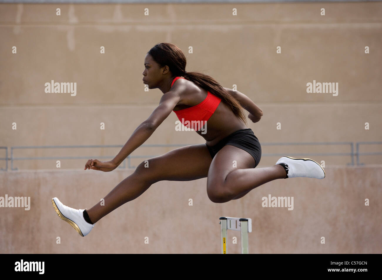 Runner jumping over hurdles on track Stock Photo - Alamy