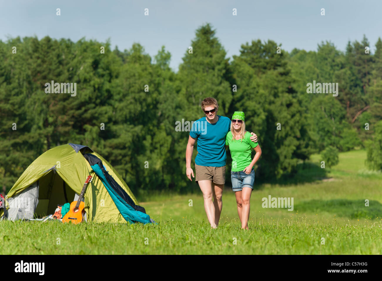 Young camping couple hugging in summer countryside tent in background ...