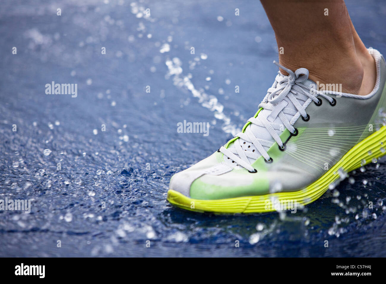 Running shoe splashing water on track Stock Photo - Alamy