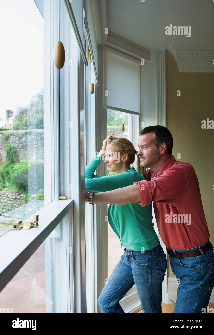Couple standing by window together Stock Photo - Alamy