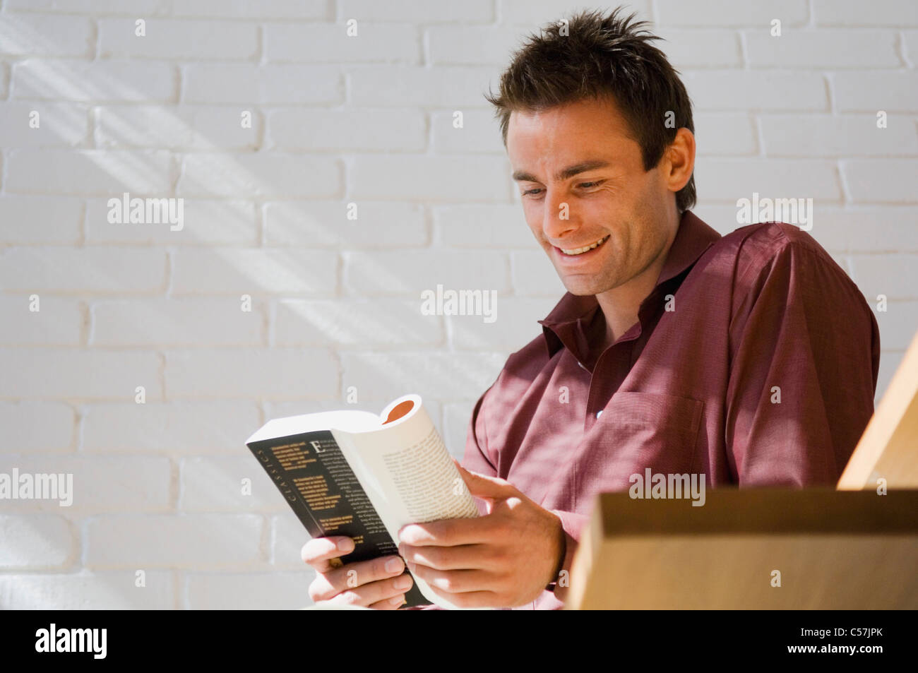 Smiling man reading book Stock Photo - Alamy
