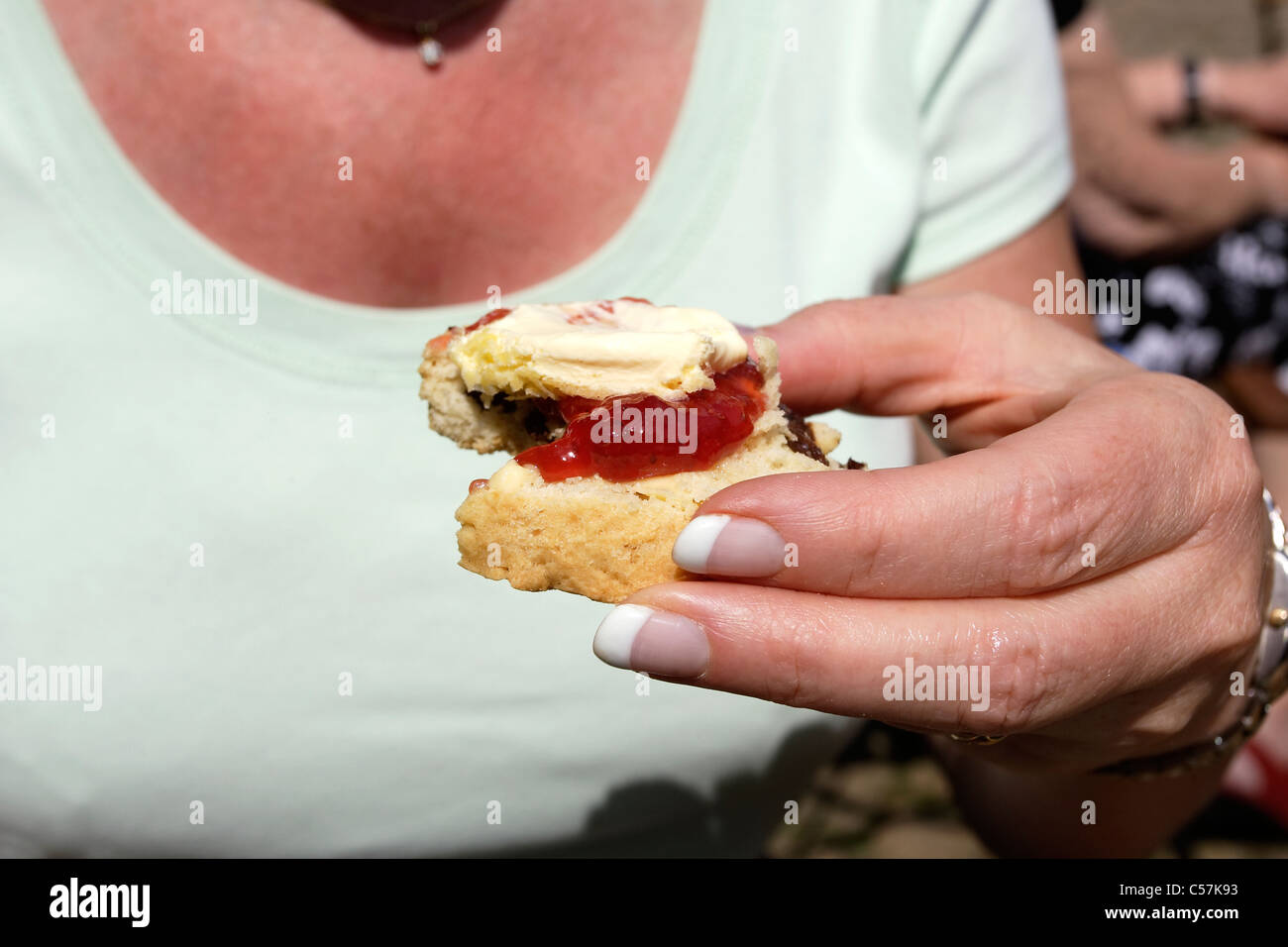 A young woman eating a scone with clotted cream and jam Stock Photo - Alamy