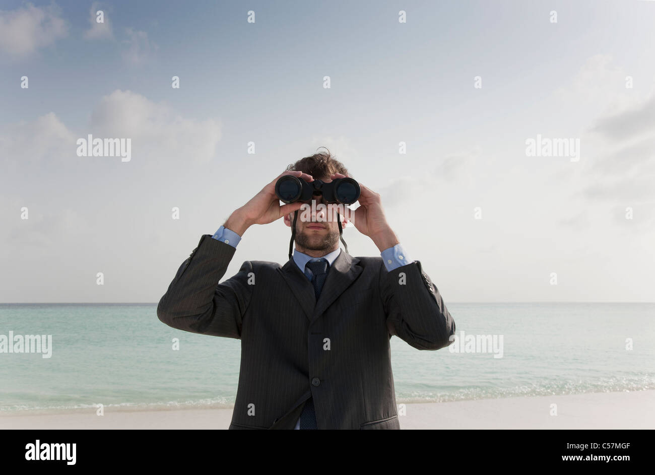 Businessman using binoculars on beach Stock Photo - Alamy