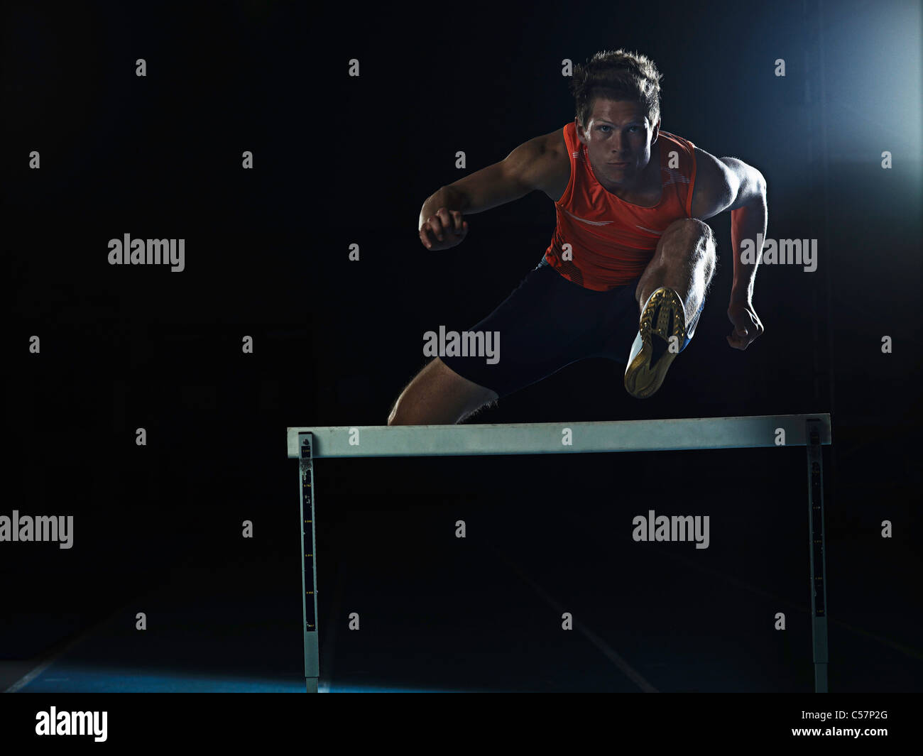 Runner jumping over hurdle on track Stock Photo - Alamy