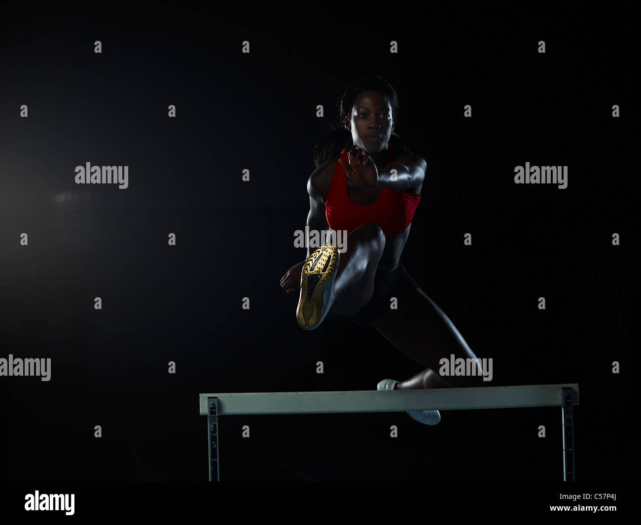 Runner jumping over hurdle on track Stock Photo - Alamy