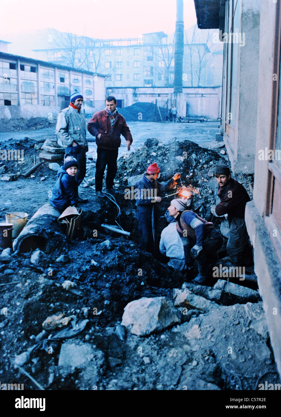 Workmen accompanied by their children try to repair roads in the ...