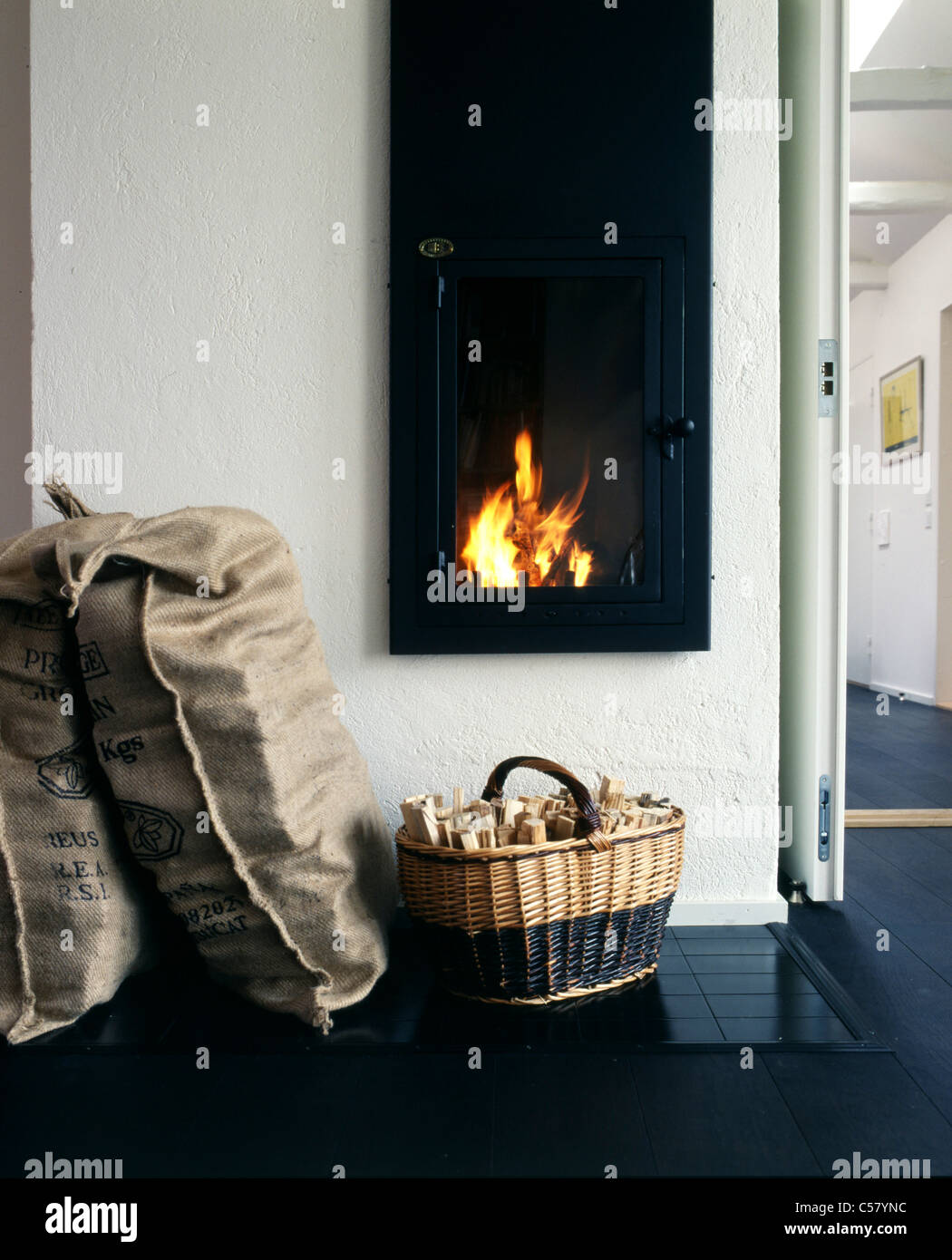 Vertical modern fireplace with sacks and wicker basket of kindling wood ...
