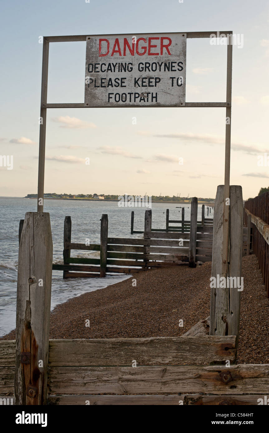 Danger decaying wooden groynes sign Stock Photo - Alamy