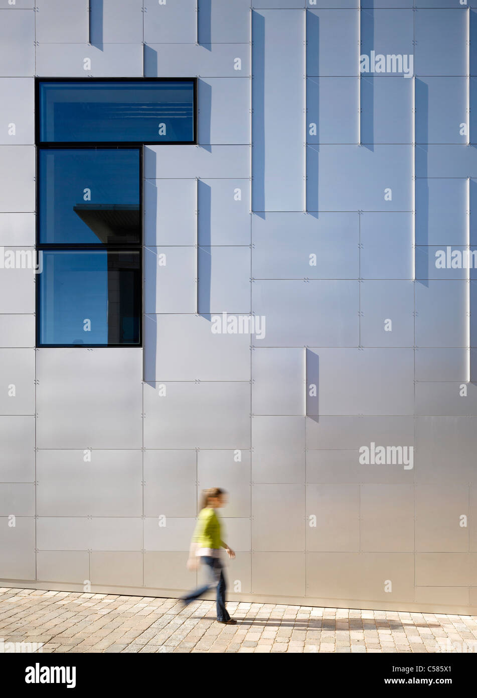 Female figure walking past the cladded facade of Cornerstone Arts ...