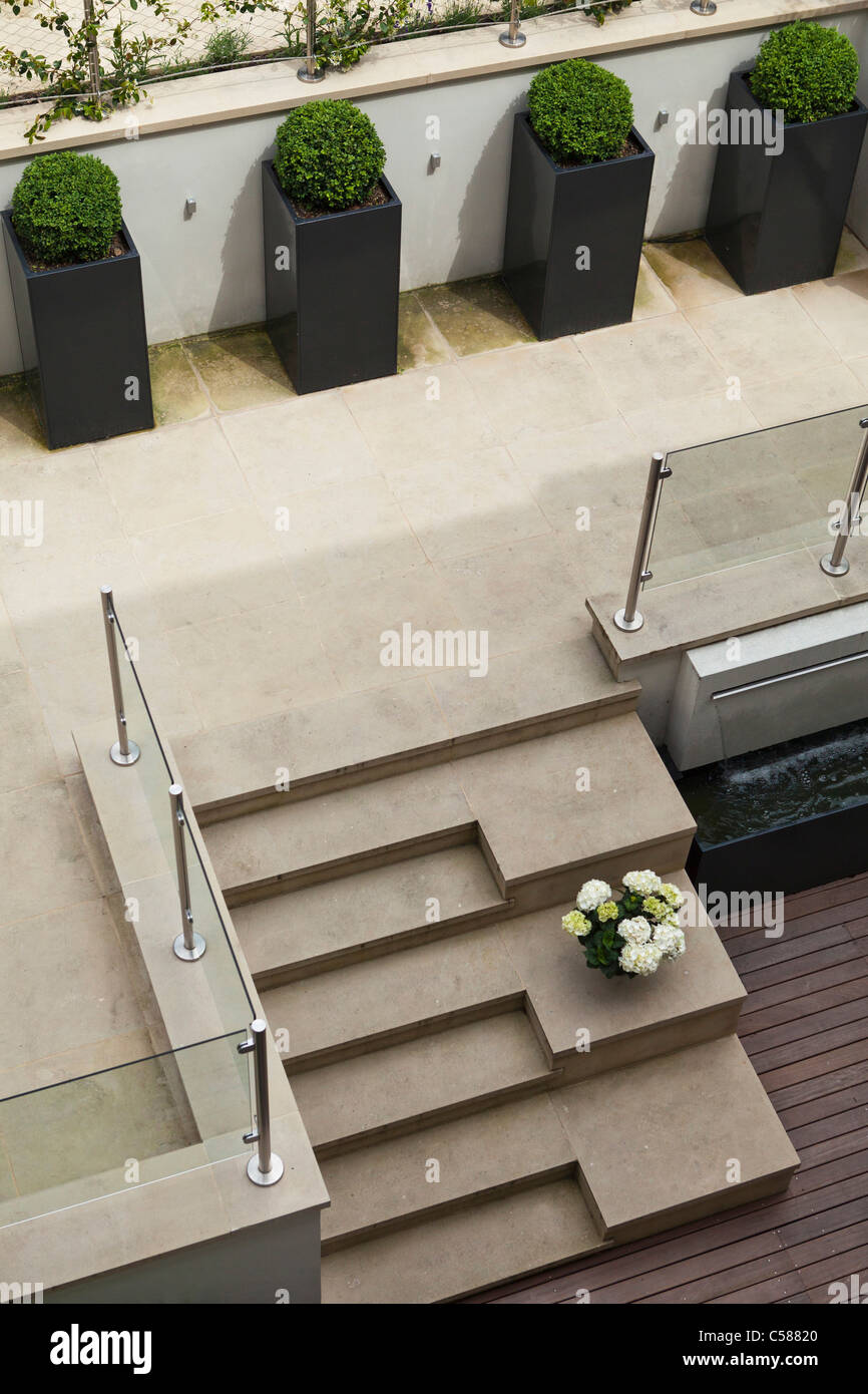 Topiary balls in powder-coated steel containers along the retaining ...