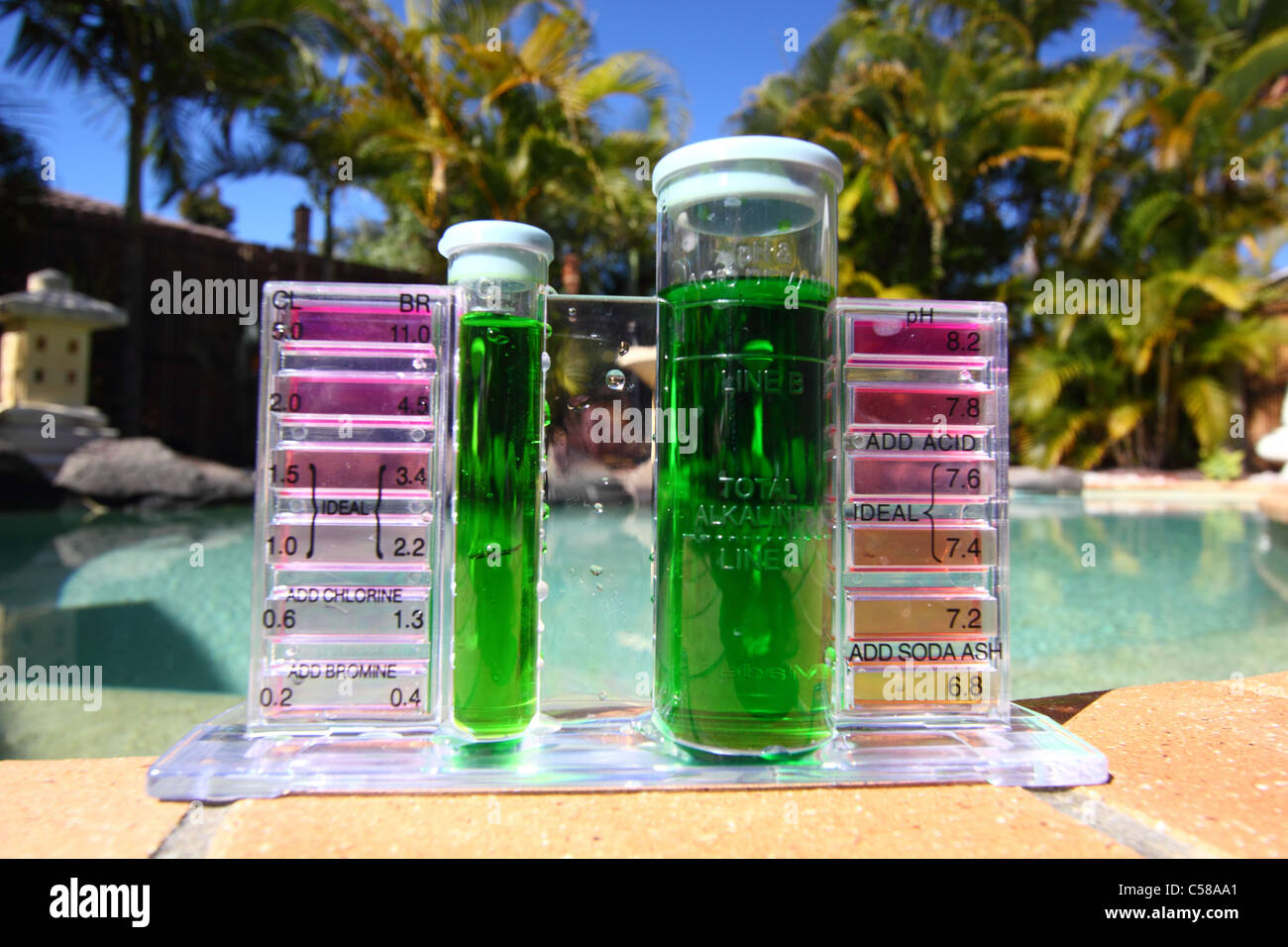 SAMPLE OF SLIMY GREEN WATER IN A POOL TEST KIT BLUE SKY AND POOLSIDE ...