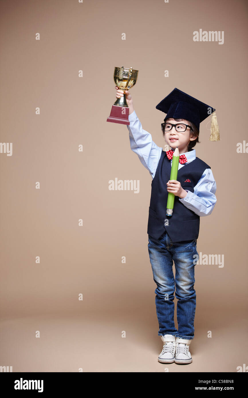 boy pick up the trophy wearing graduation cap Stock Photo - Alamy