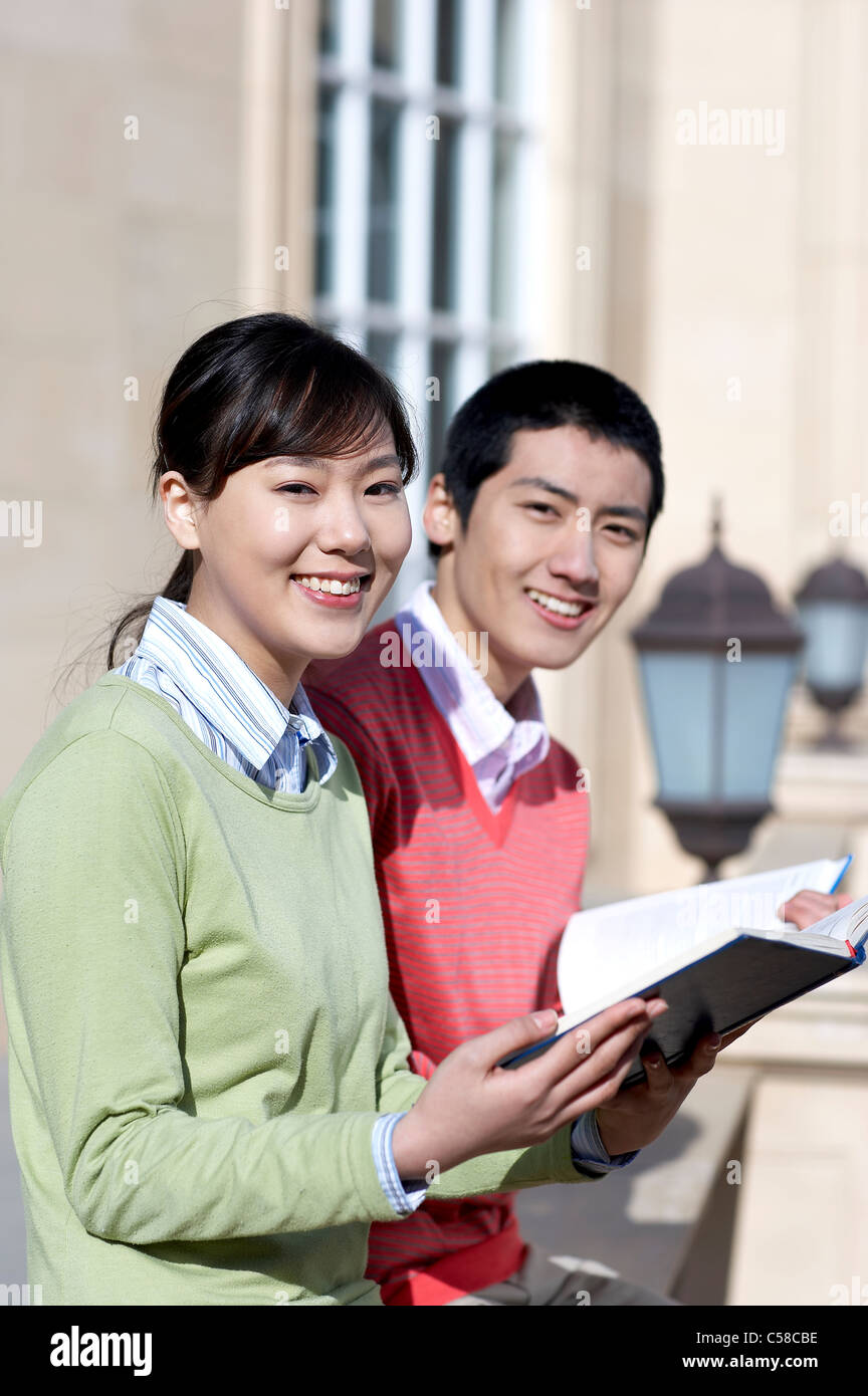 Portrait of teens sitting on railing, reading book Stock Photo - Alamy