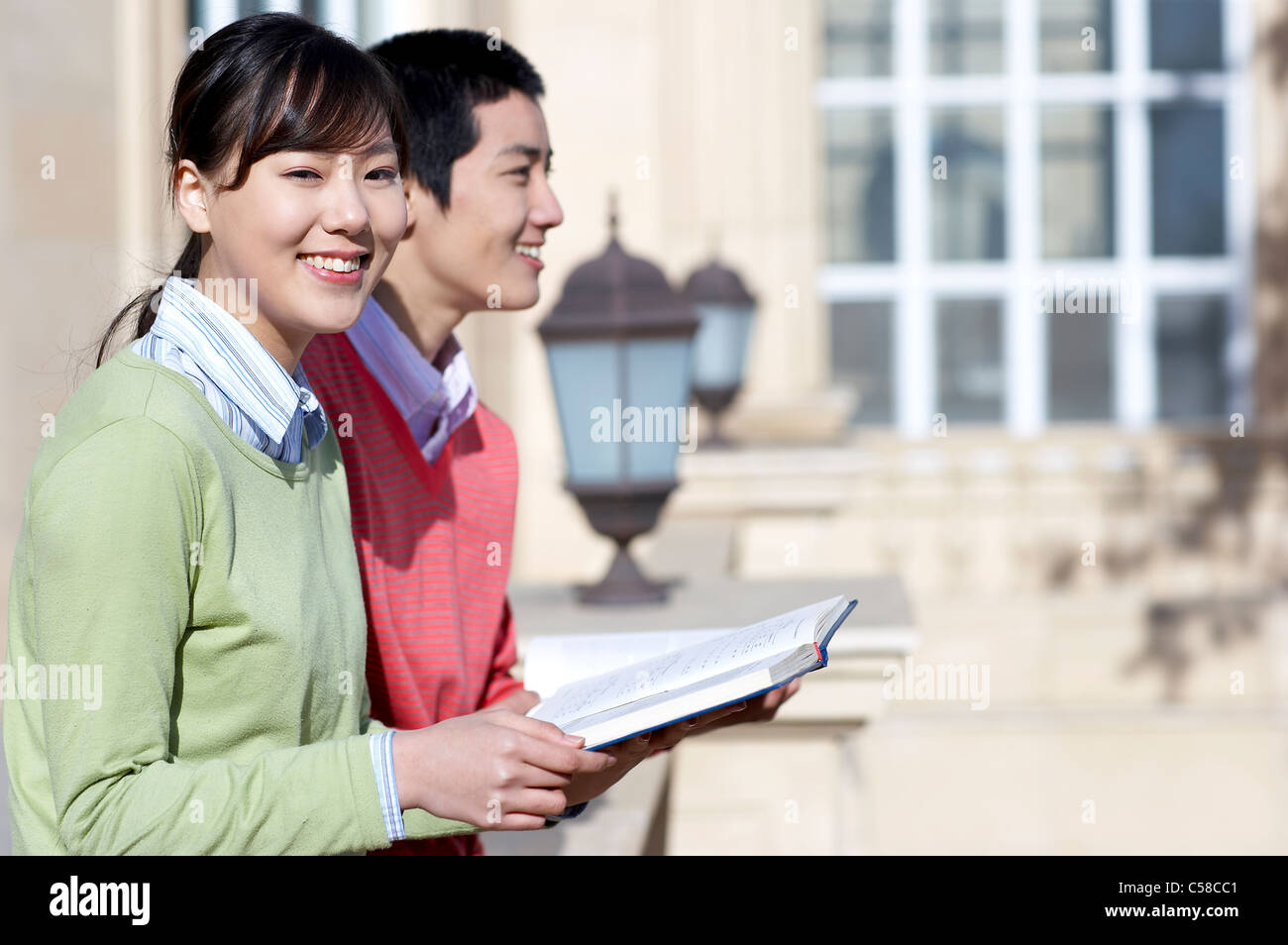 Portrait of teens sitting on railing, reading book Stock Photo - Alamy