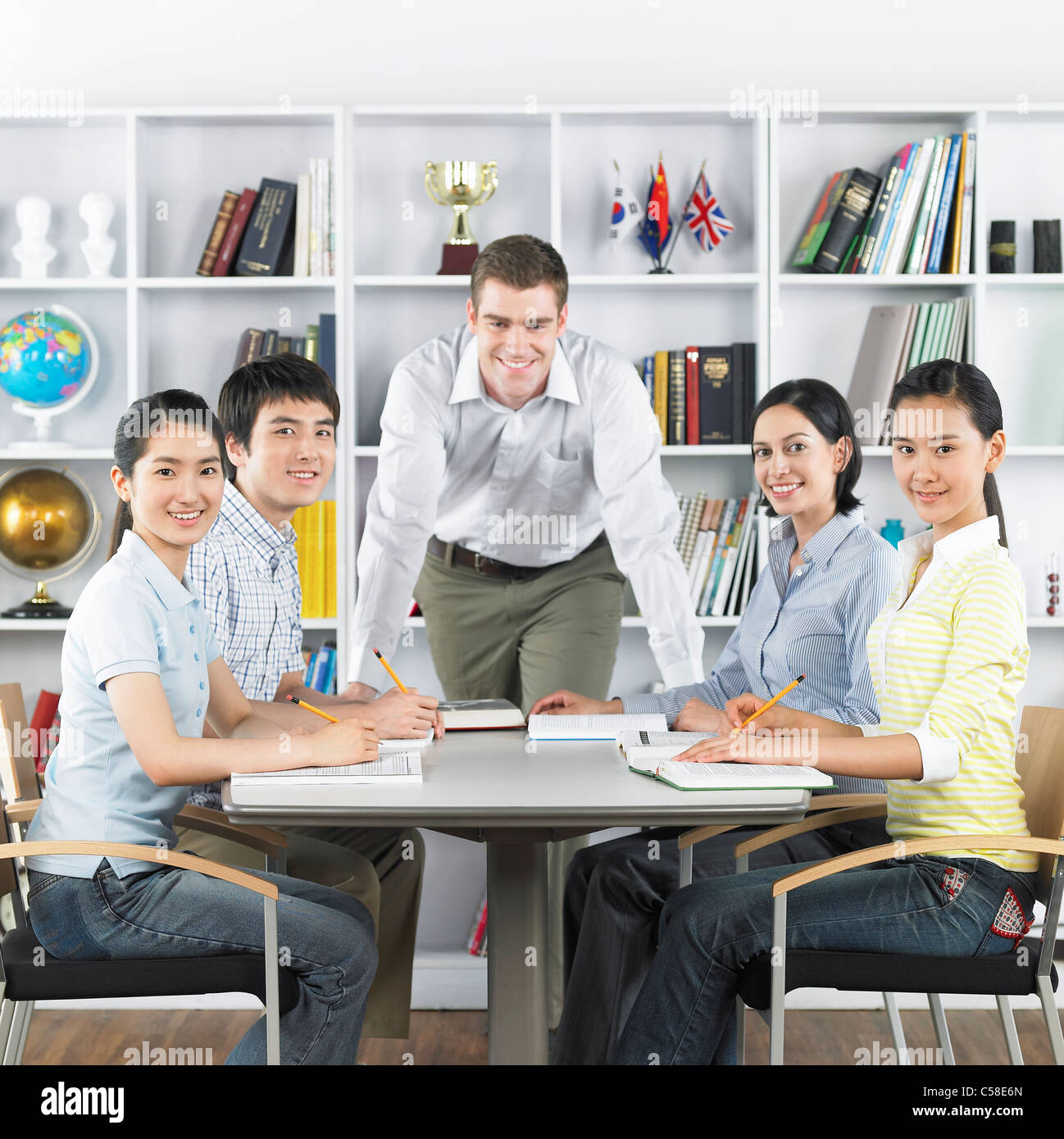 Portrait of teacher with students in room Stock Photo - Alamy