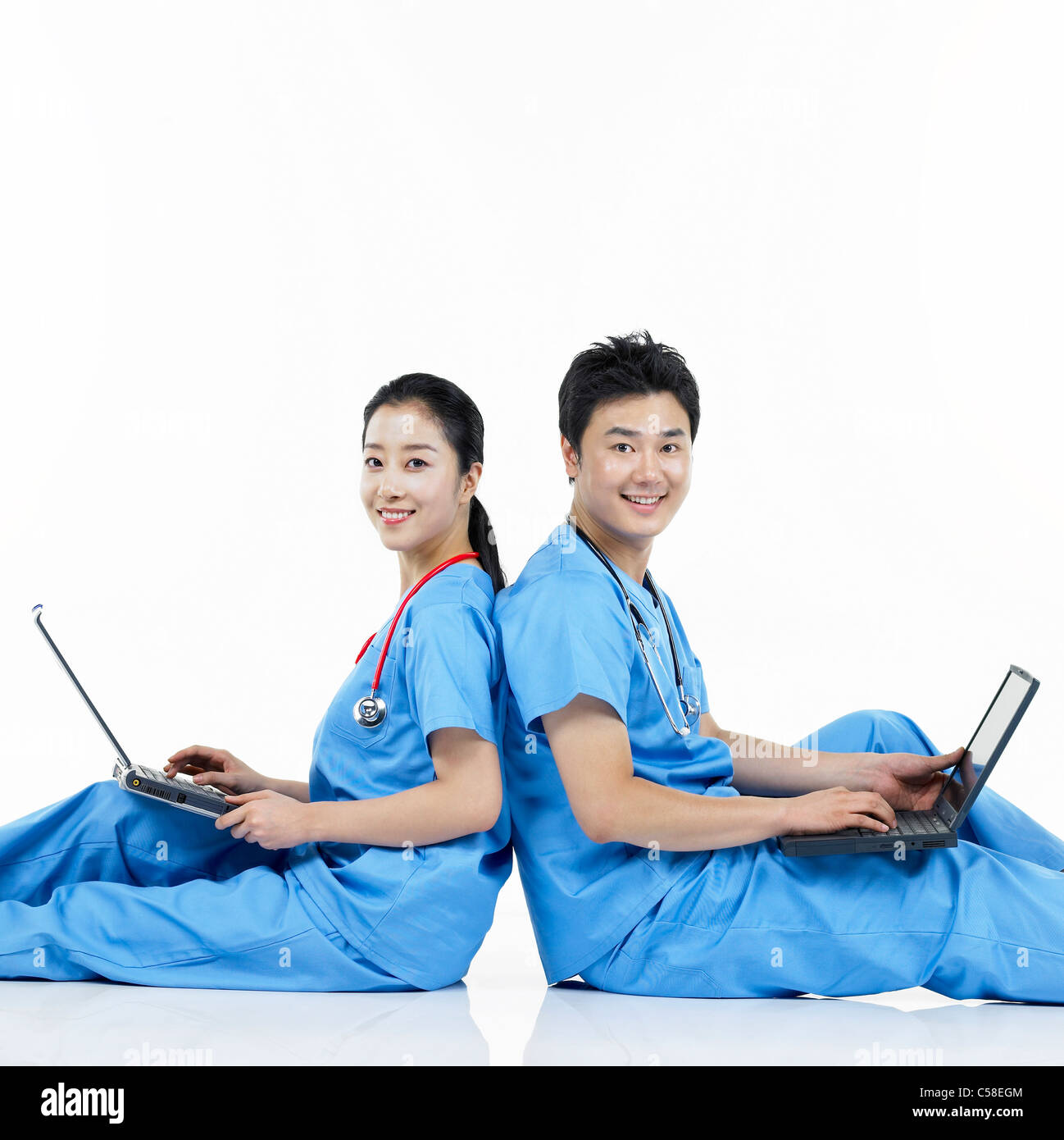 Portrait of Doctors using laptop sitting back to back Stock Photo - Alamy
