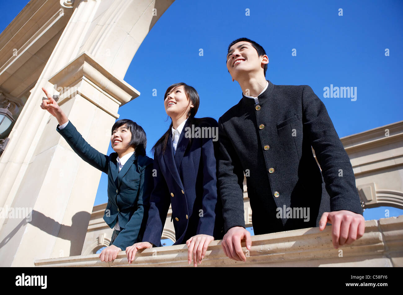 Side view of teens standing with college in background Stock Photo - Alamy